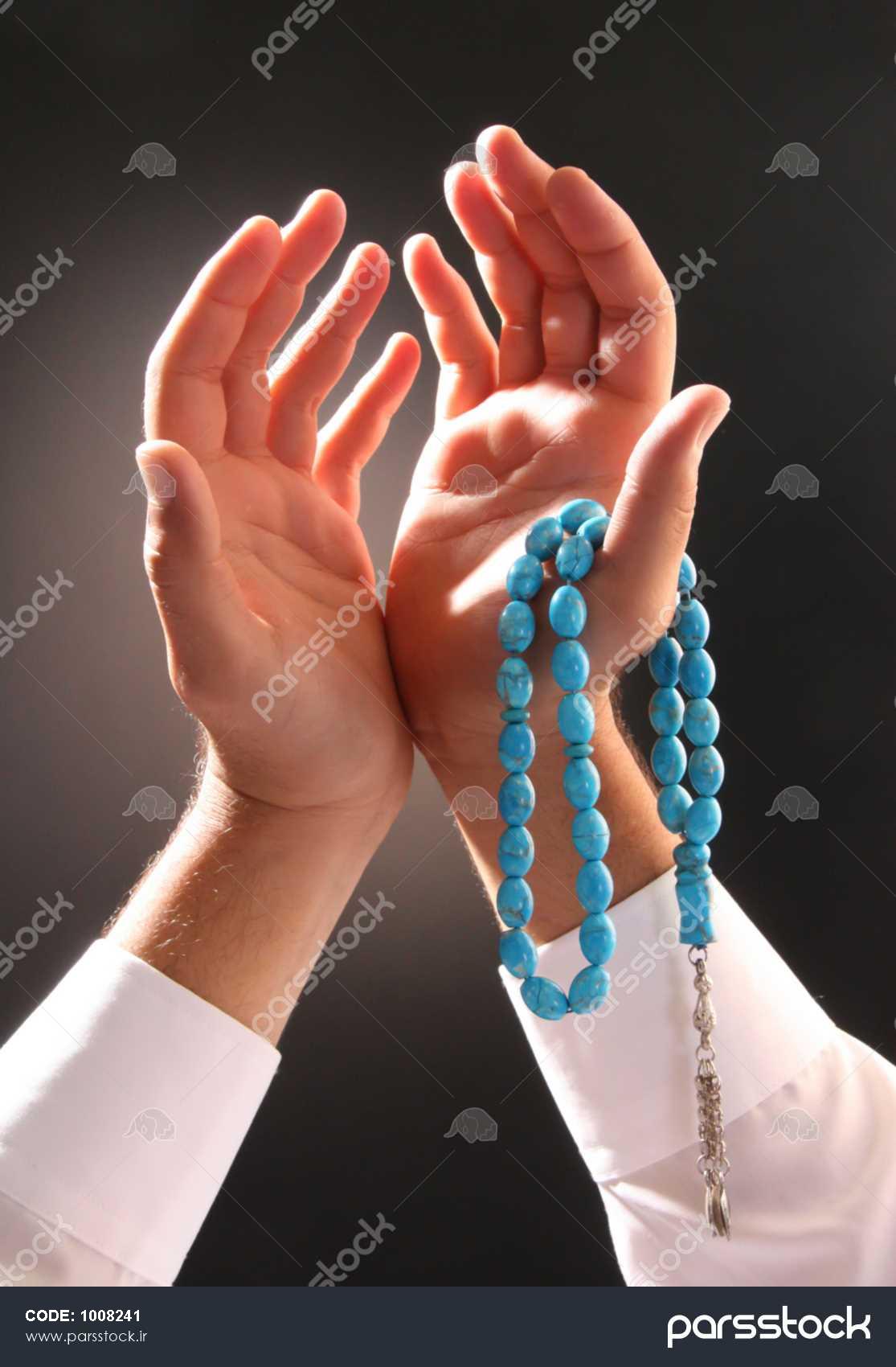 دست مردی که تسبیح را در حالت دعا و درخواست در دست گرفته است 1008241